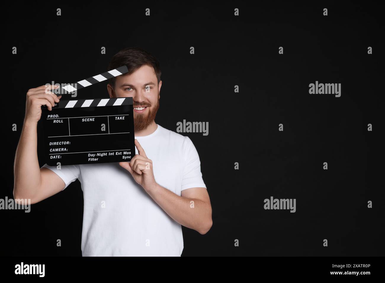 Making movie. Smiling man with clapperboard on black background. Space ...