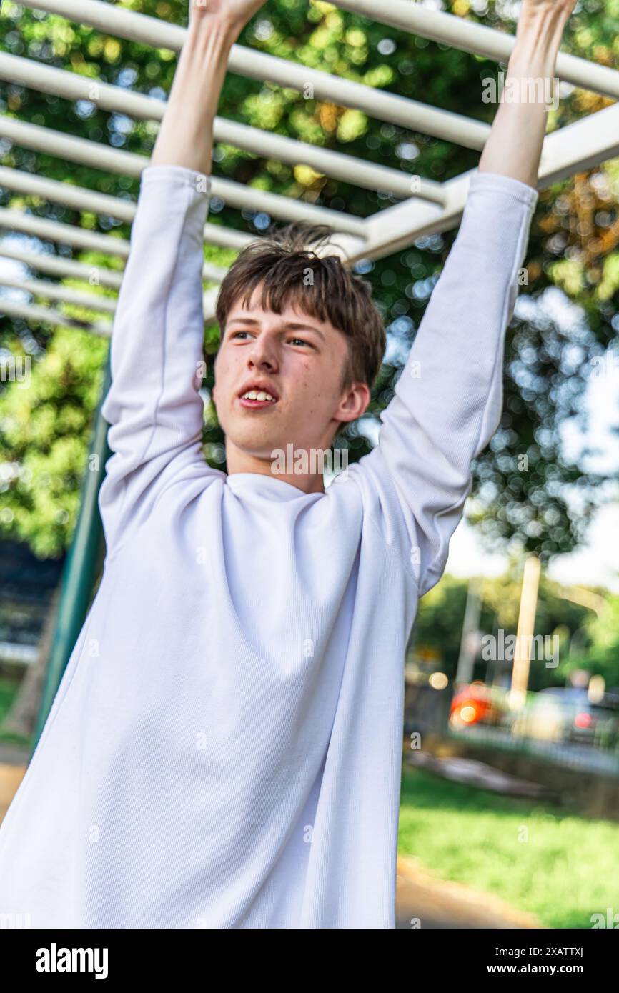 This image shows a young boy hanging from a set of monkey bars. He is ...