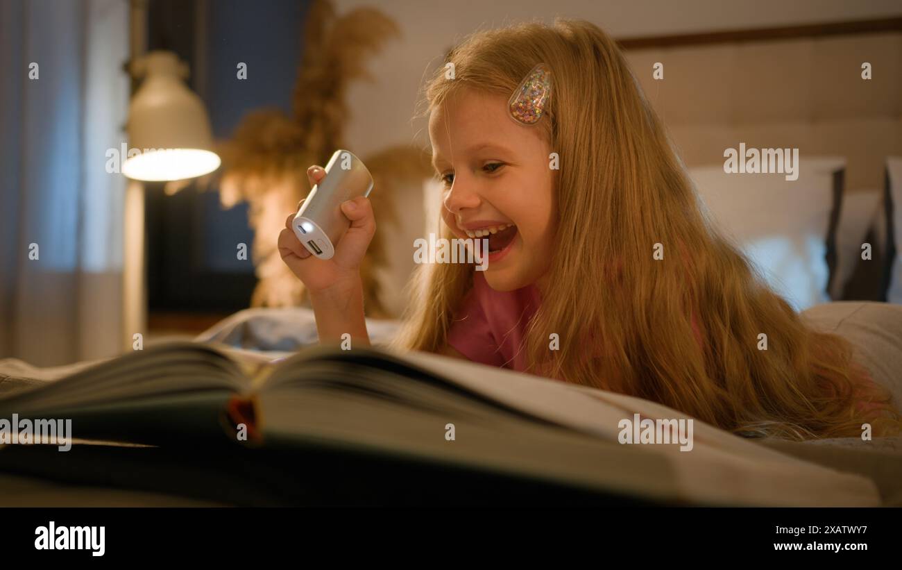 Joyful laughing Caucasian girl little child reading funny amusing book ...