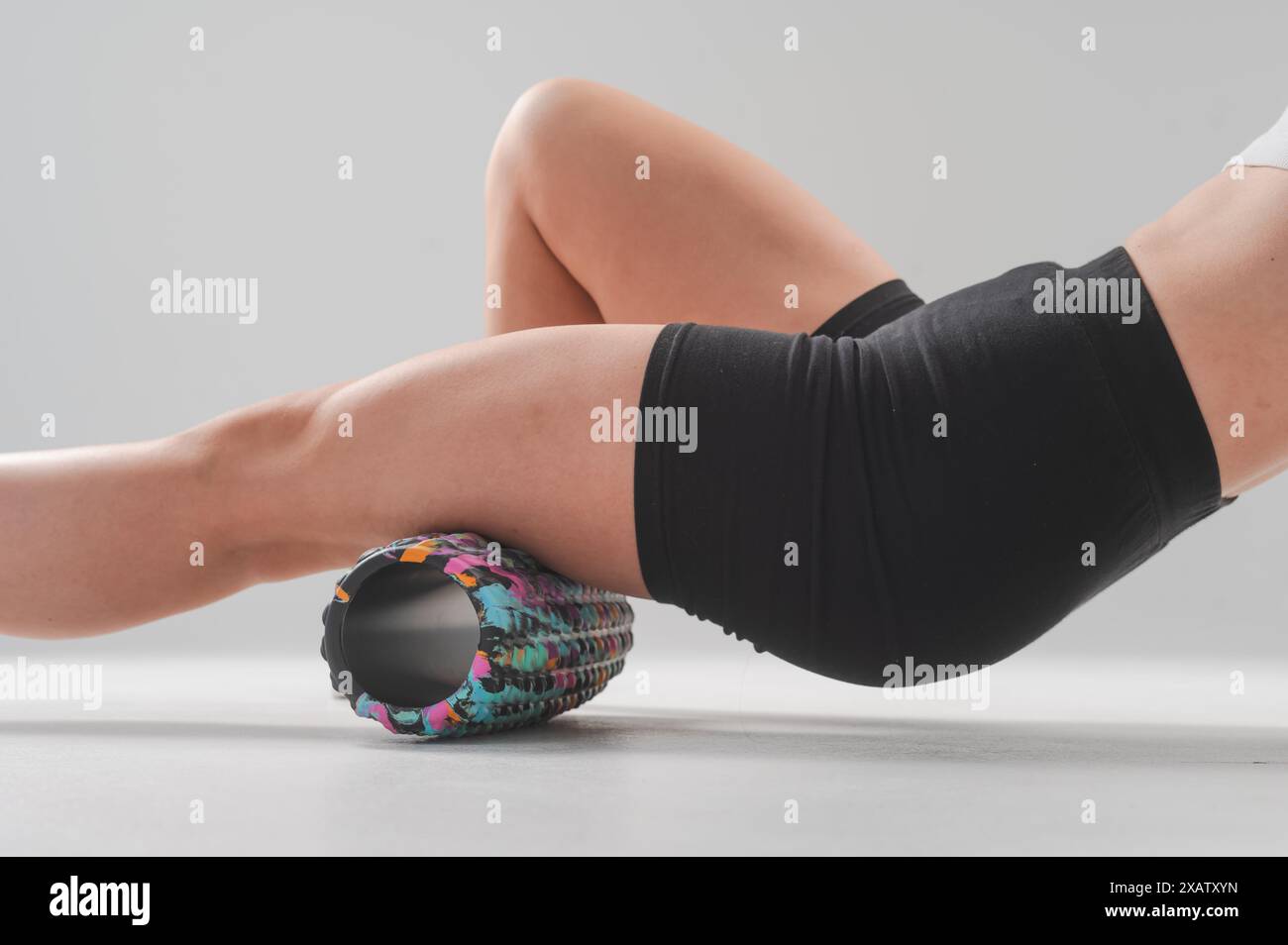 Faceless woman doing roller exercise for myofascial release on white ...