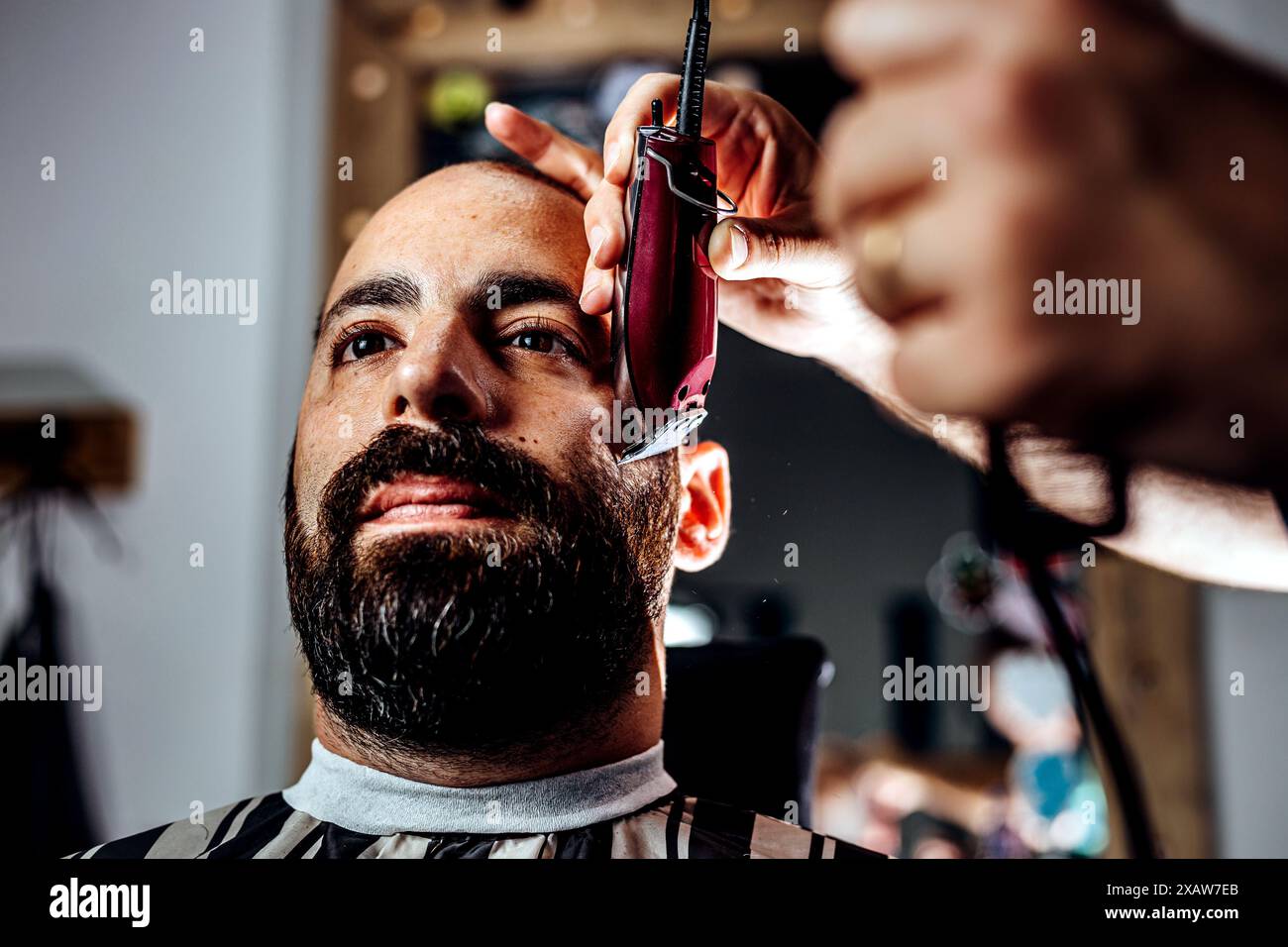 Barber cutting beard of customer with hair trimmer Stock Photo - Alamy