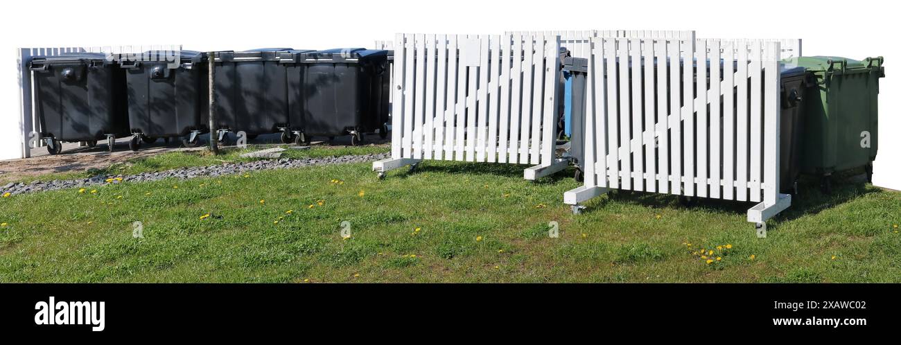 Garbage containers in the park are blocked by a white wooden fence ...