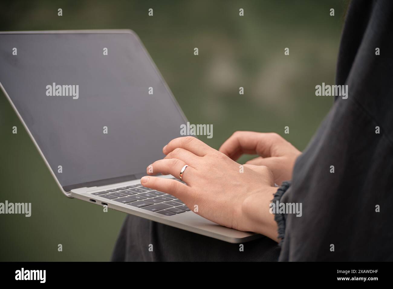 A woman is typing on a laptop with a ring on her finger. Concept of ...