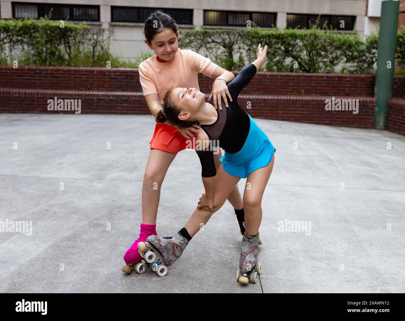 Two young girls in colorful outfits practice a skating pose together in ...