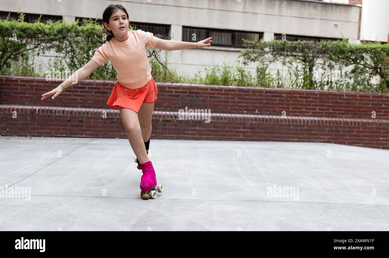 A young girl in an orange skirt and peach top strikes a pose while ...