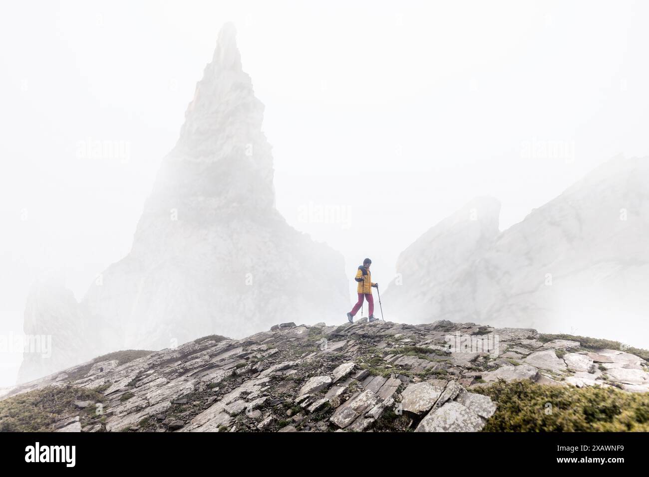 woman walking on the mountain in the fog with pink and yellow clothes ...