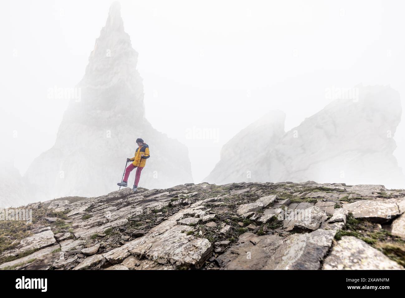 woman walking on the mountain in the fog with pink and yellow clothes ...