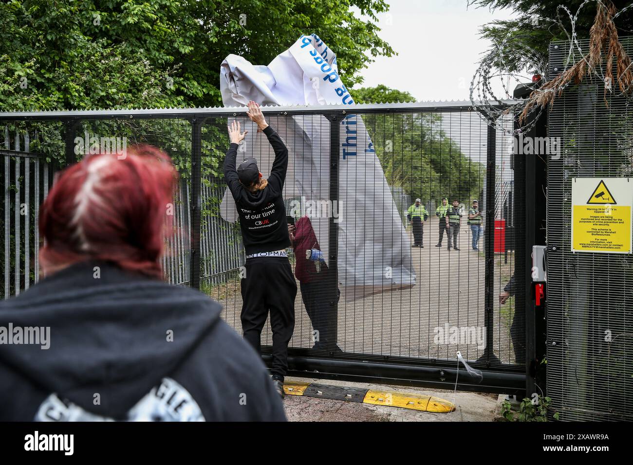 A protester pulls down the main gate banner that states 'Thriving Dogs ...