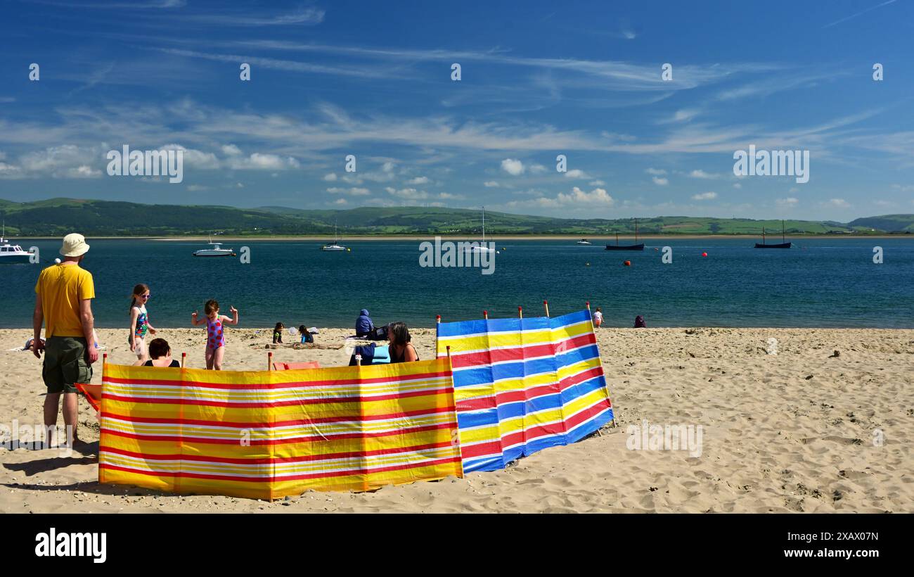Family on Aberdyfi beach (Aberdovey) with colourful wind-breaks, blue ...