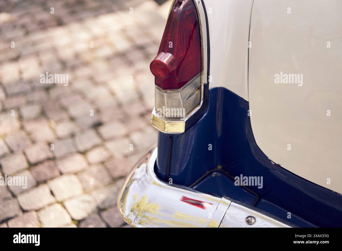 A vintage car tail light illuminates a cobbled street, embodying ...