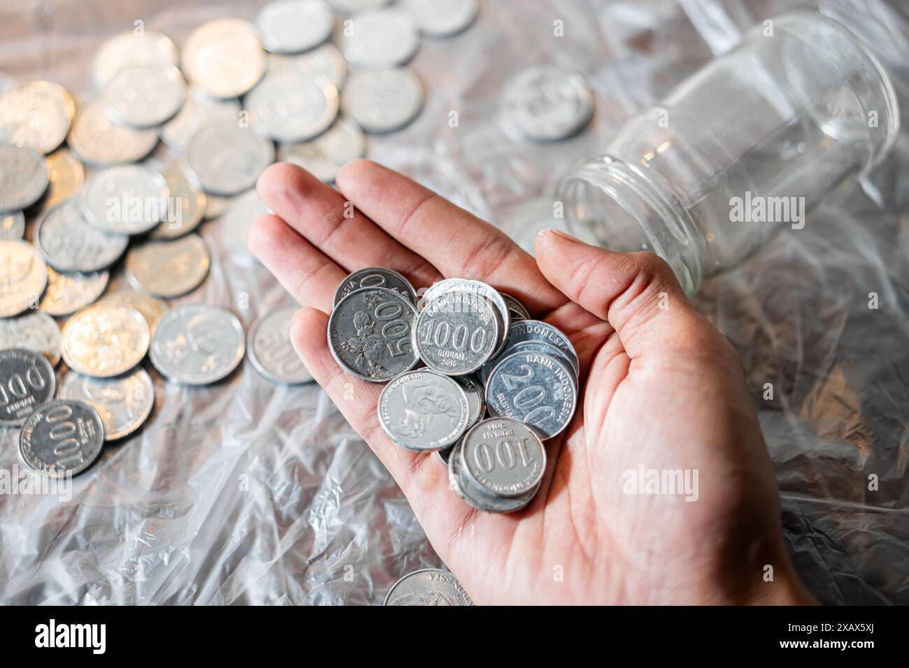 A hand holding several South Korean won coins with more coins and an ...