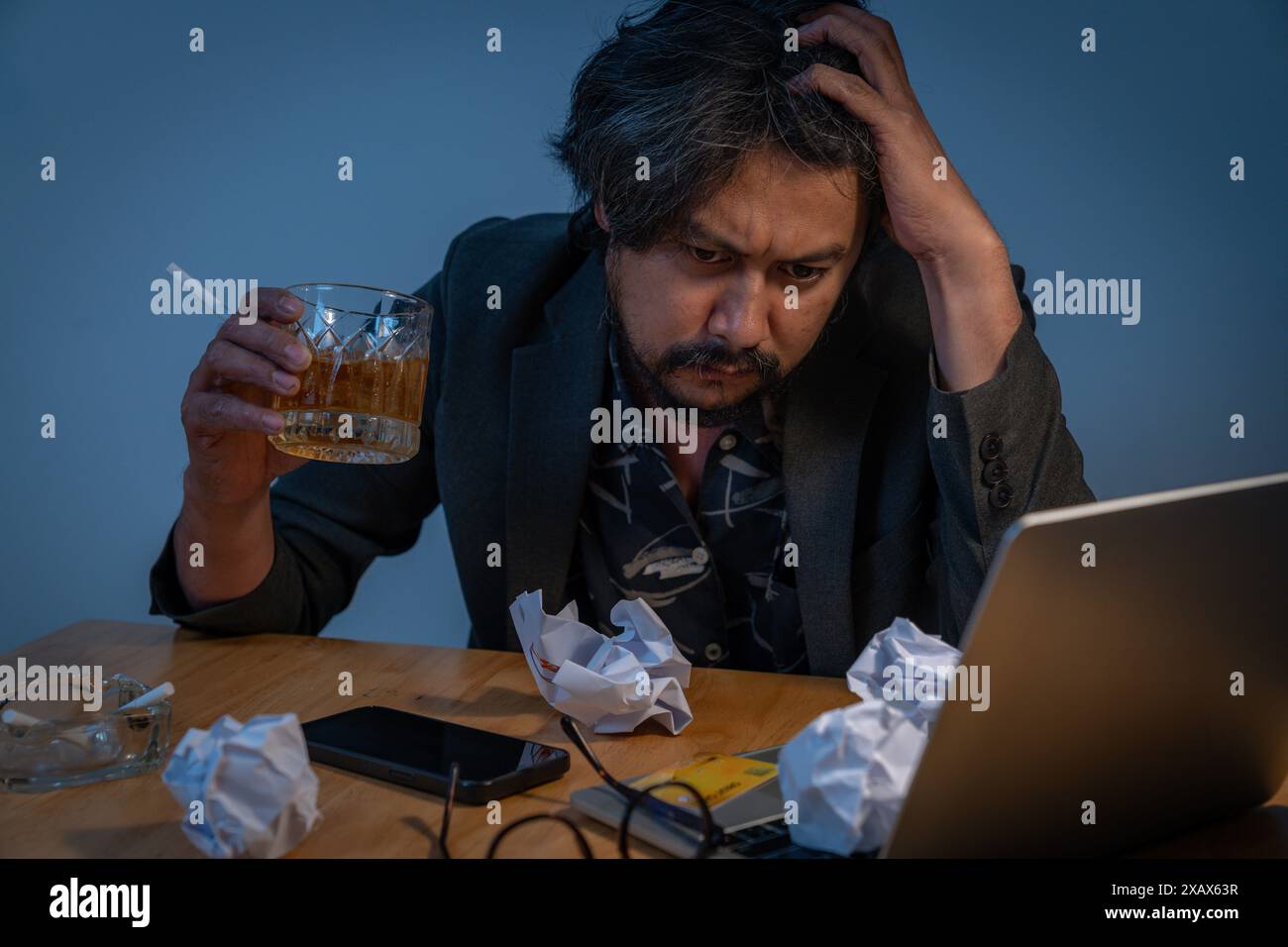 A young office worker, having failed in business, sits drinking alcohol ...