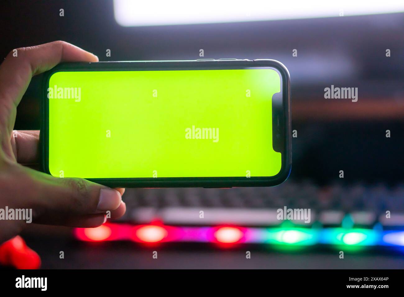 A person holding a smart phone with a bright green screen in front of a ...
