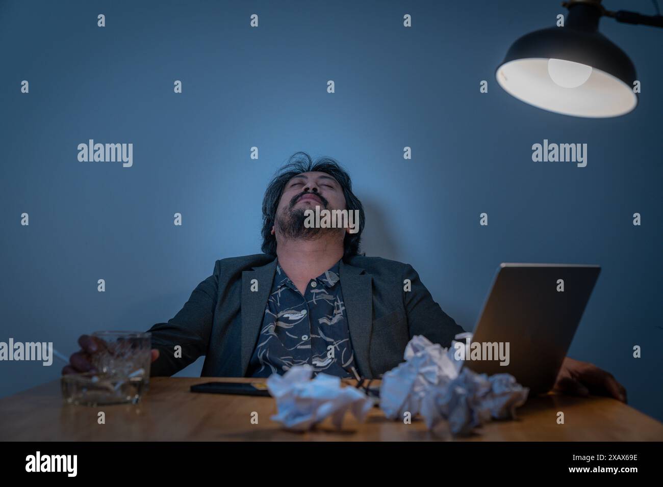 A young office worker, having failed in business, sits drinking alcohol ...