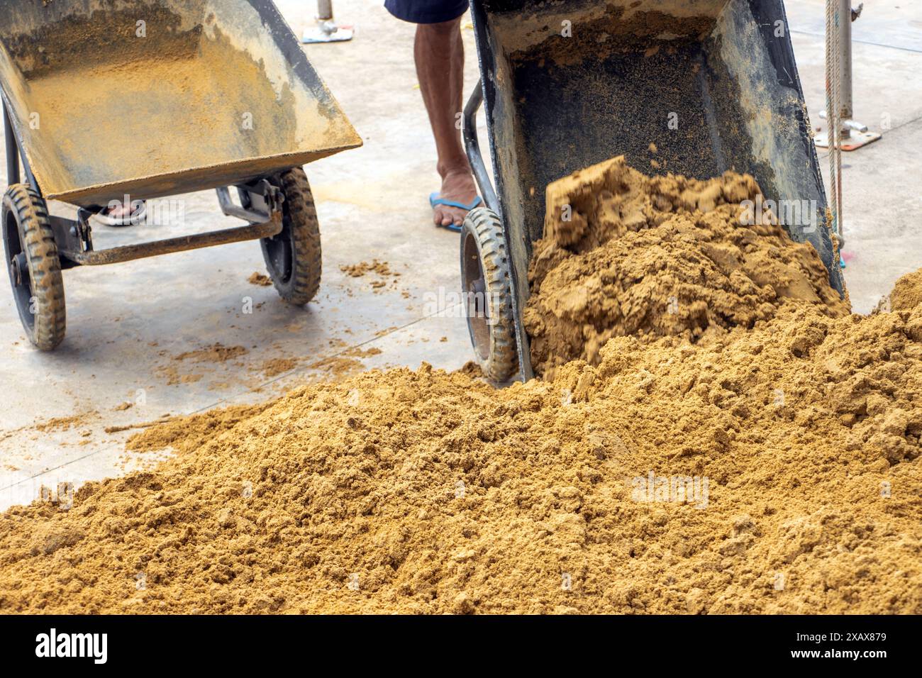 Workers dump sand from wheelbarrows onto the pile Stock Photo - Alamy
