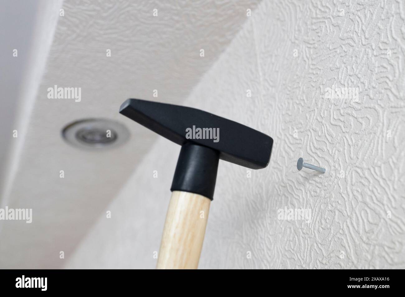 hammer hammers nail into white wall at home Stock Photo - Alamy