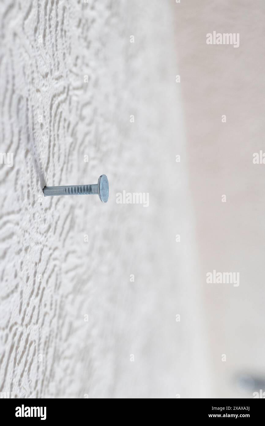 steel nail driven into white wall close up Stock Photo - Alamy