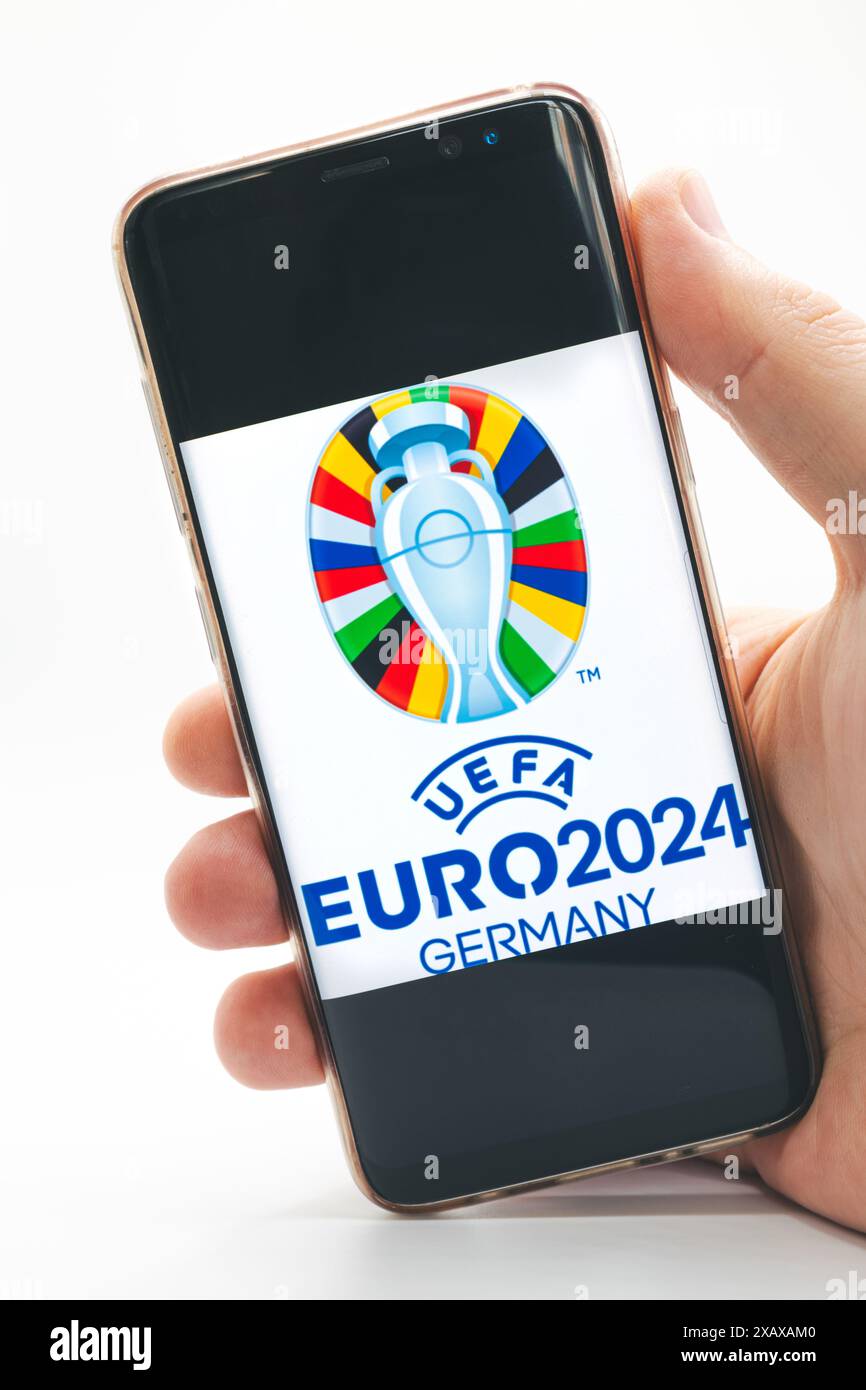 A man is holding a smartphone with the official logo of the UEFA ...