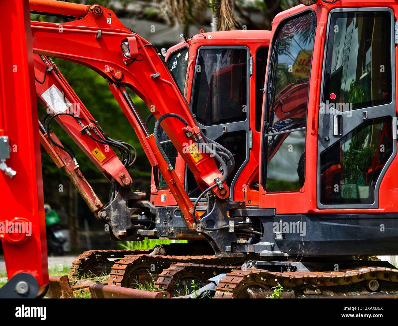 Red large excavators are stationed in a green field in front of a ...