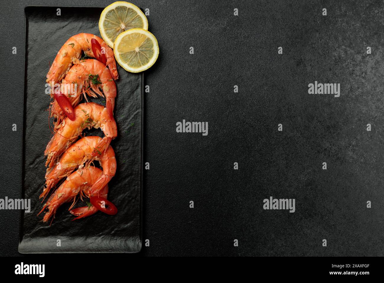 Large cooked king prawns on a black background. Lemon slices Stock ...