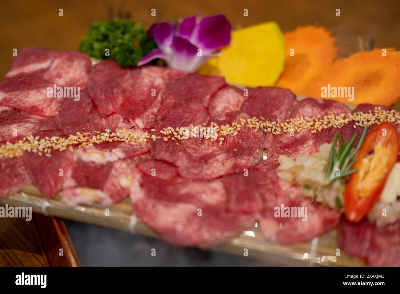 Japanese style sliced rare beef tongue meat on the plate with smoke and ...