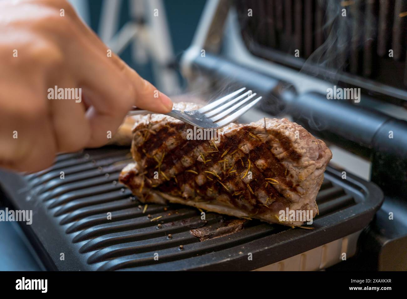 Chef at the kitchen preparing beef steaks on the home electric grill ...