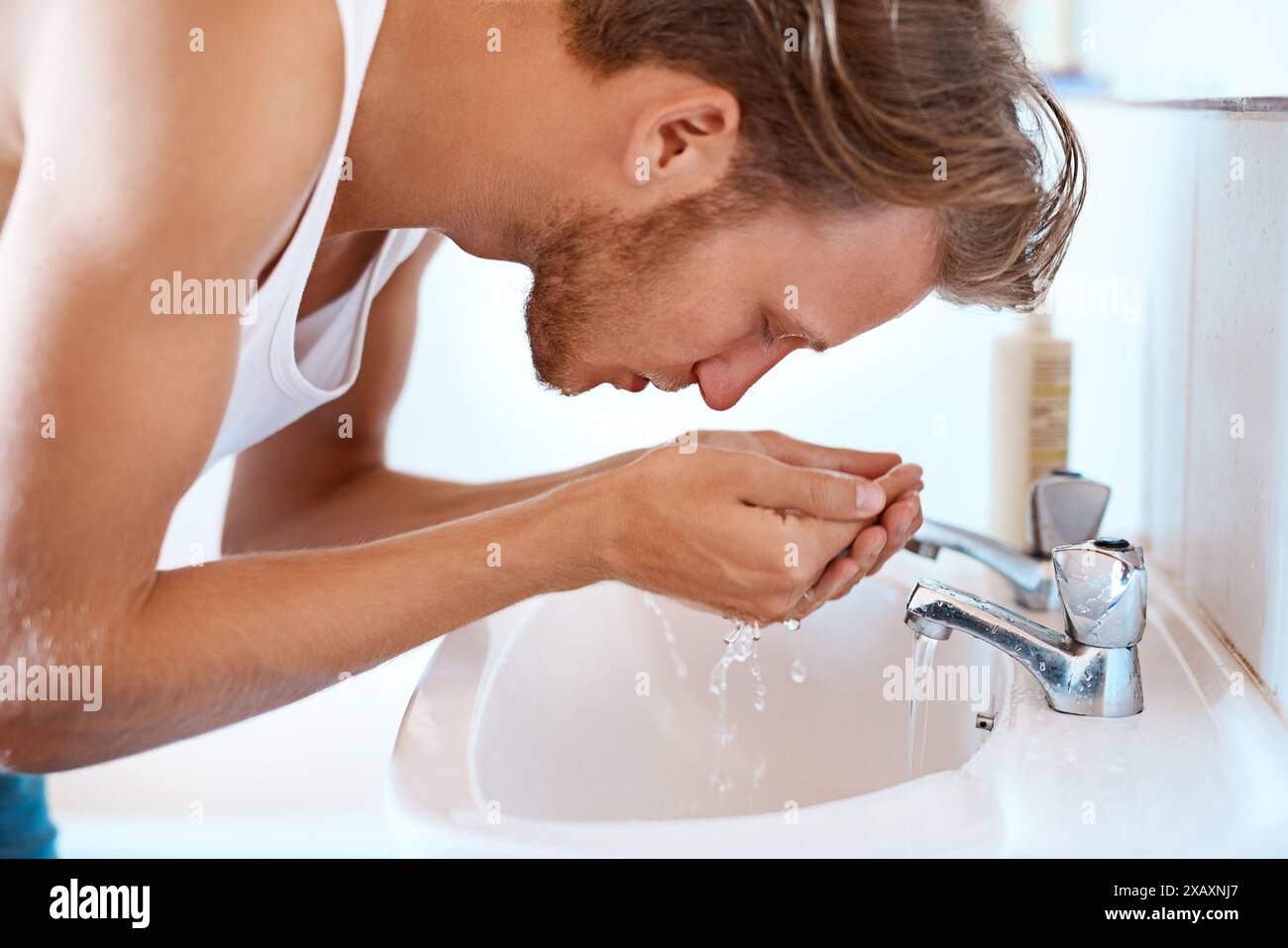 Water splash, cleaning and man in bathroom for washing face, hygiene or ...