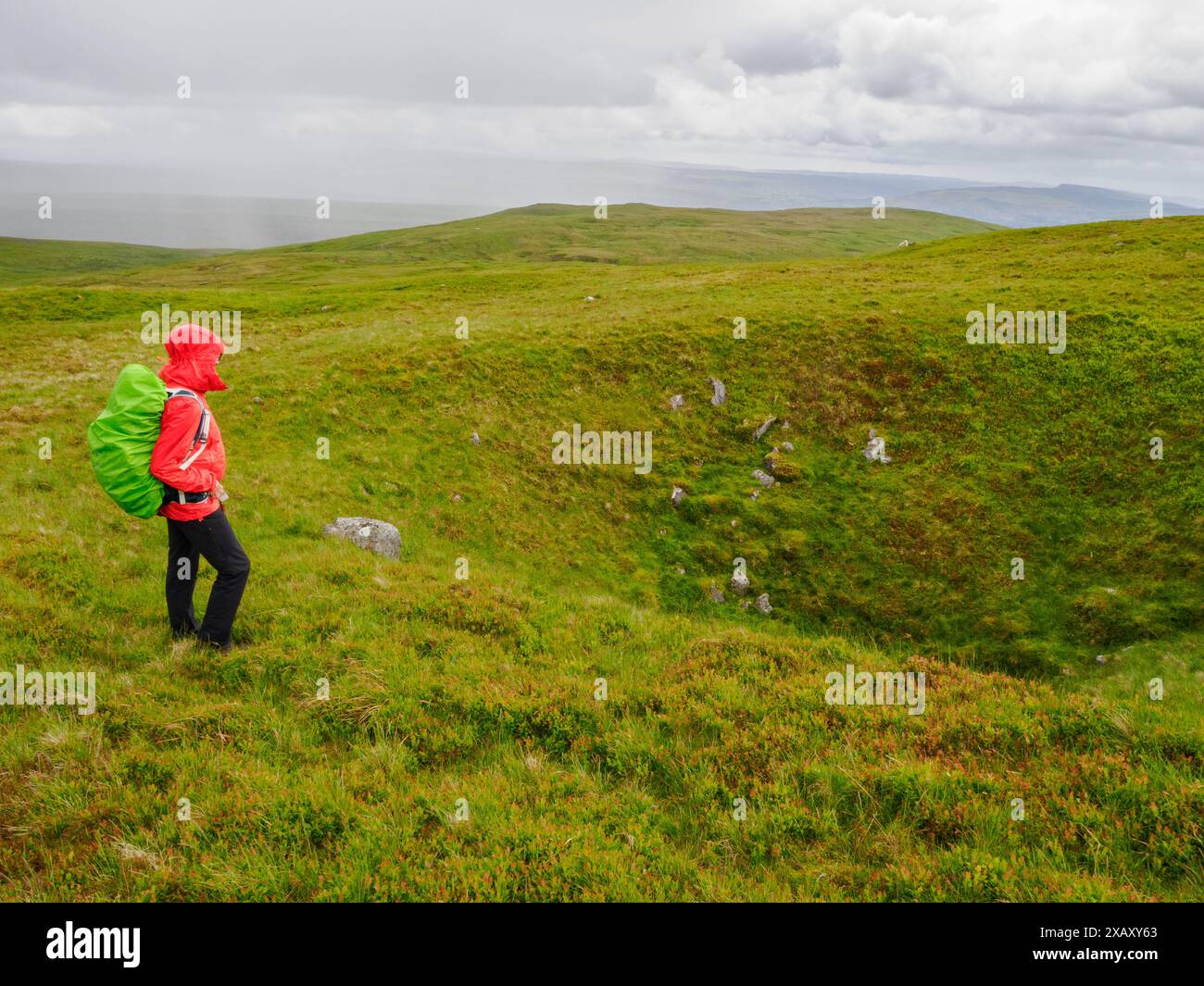 A walker looking at a large shake hole or sink hole on the Black ...