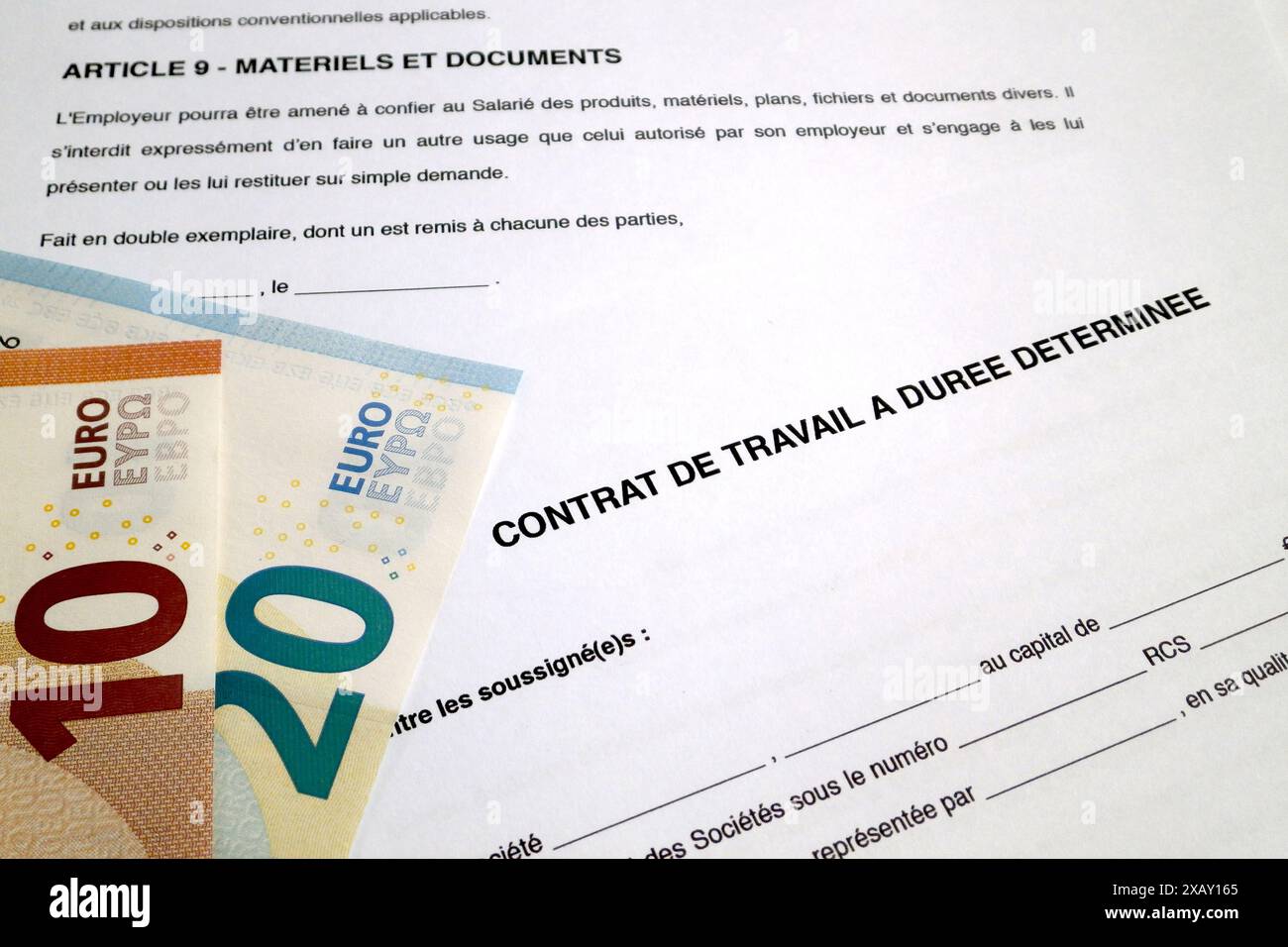 Some euro banknotes a on the top of a French Definite Duration Contract ...