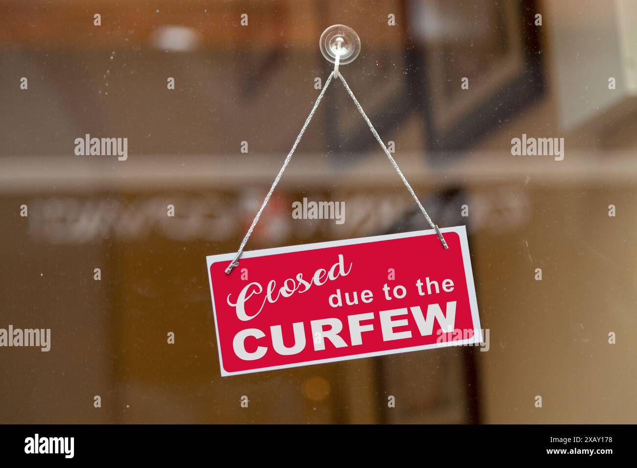 Red sign hanging at the glass door of a shop with written "Closed due ...