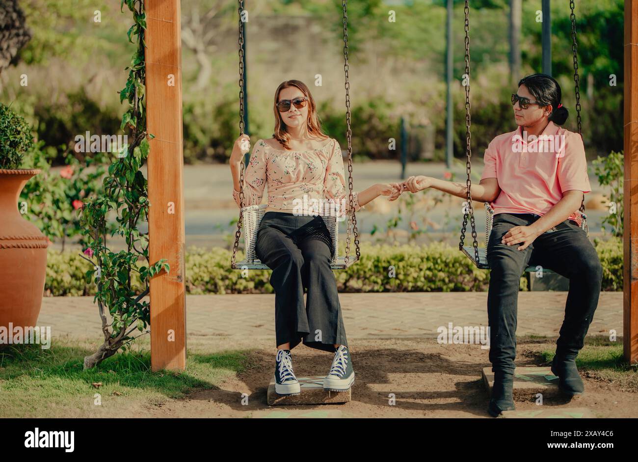 Young couple in love holding hands on a swing. Portrait of a young ...