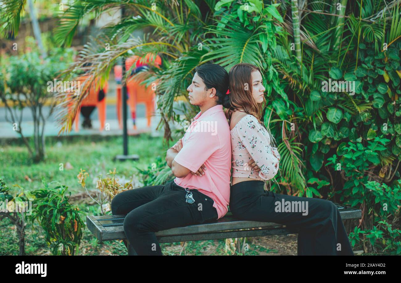 Upset young couple sitting back to back on a bench. Unhappy couple ...