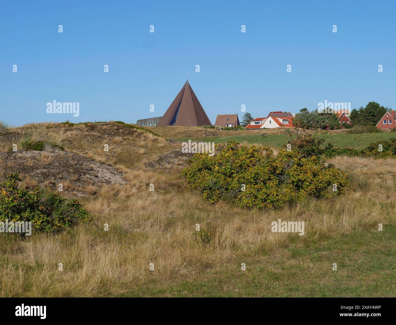 Hilly landscape with scattered houses and a pyramid-shaped tower under ...