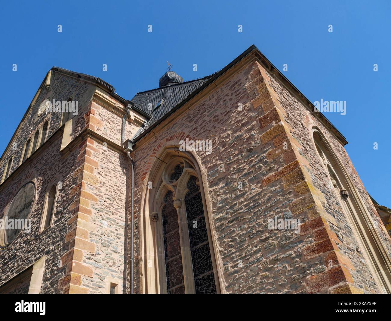 Gothic brick church under a blue sky, close-up of spire and window ...