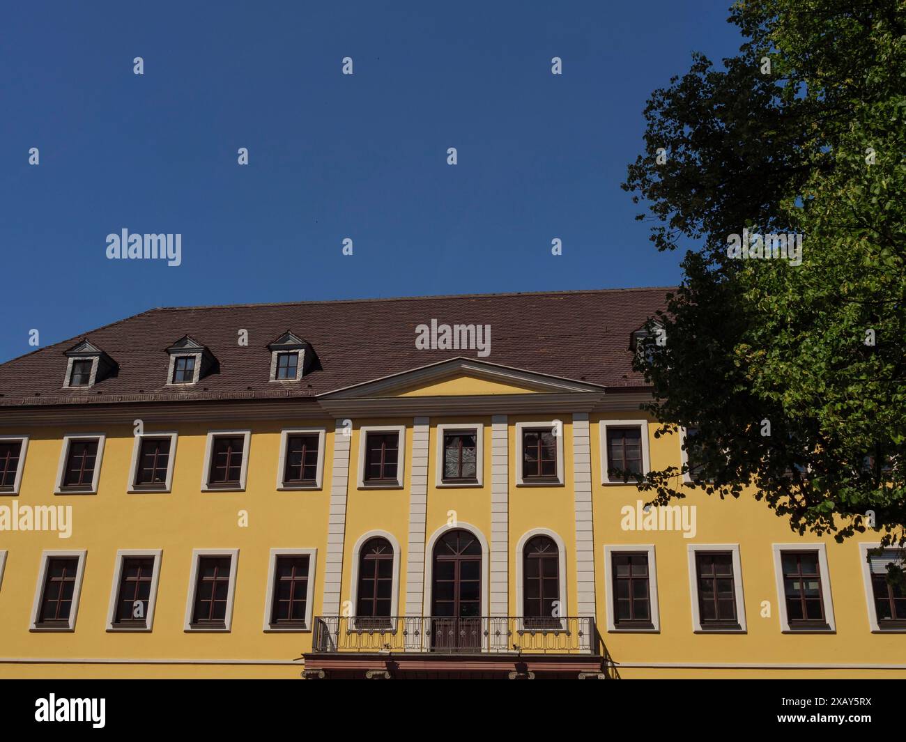 Yellow building with symmetrical facade design and large windows, on a ...