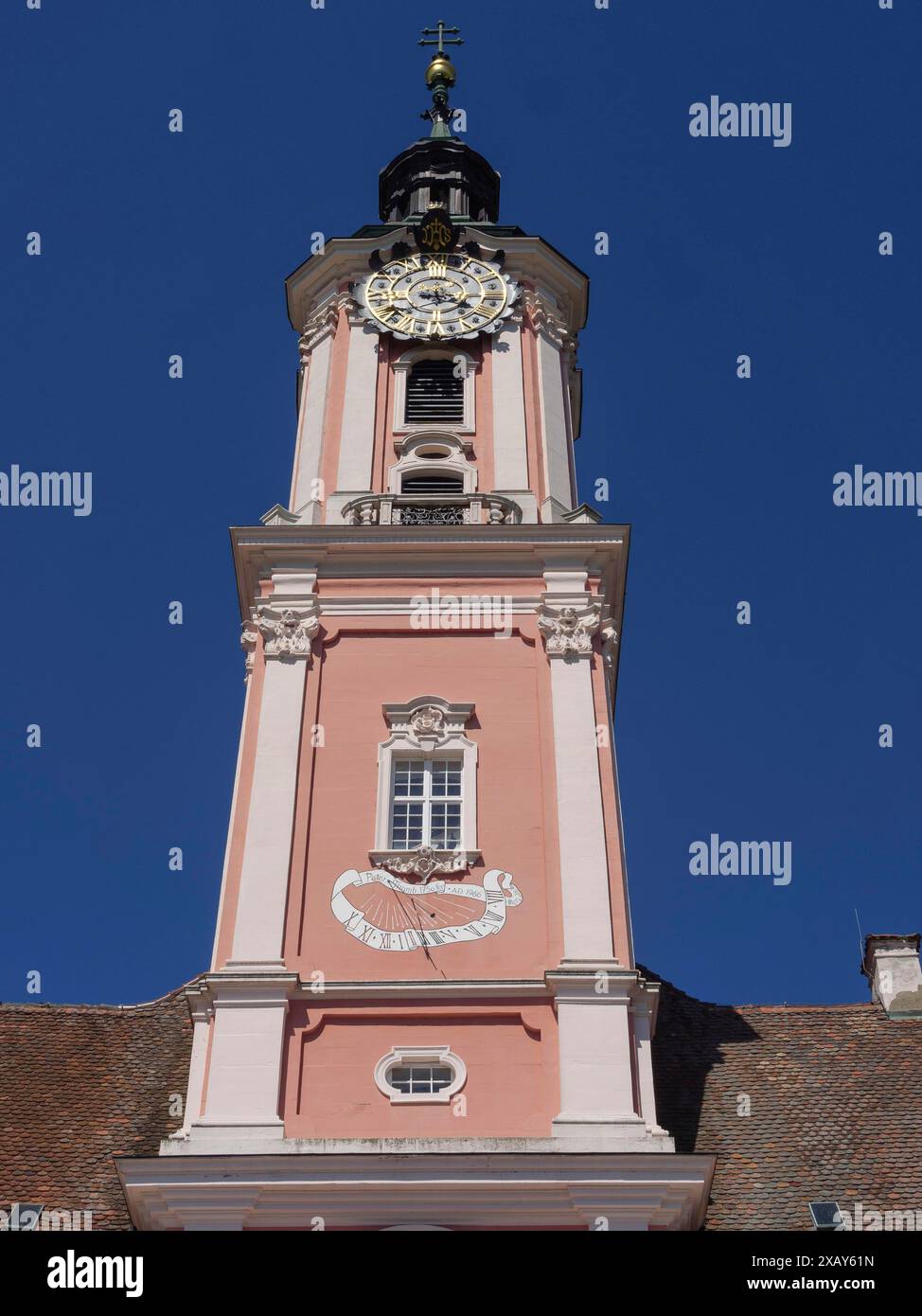 A baroque tower with a clock and pink-coloured facade against a clear ...