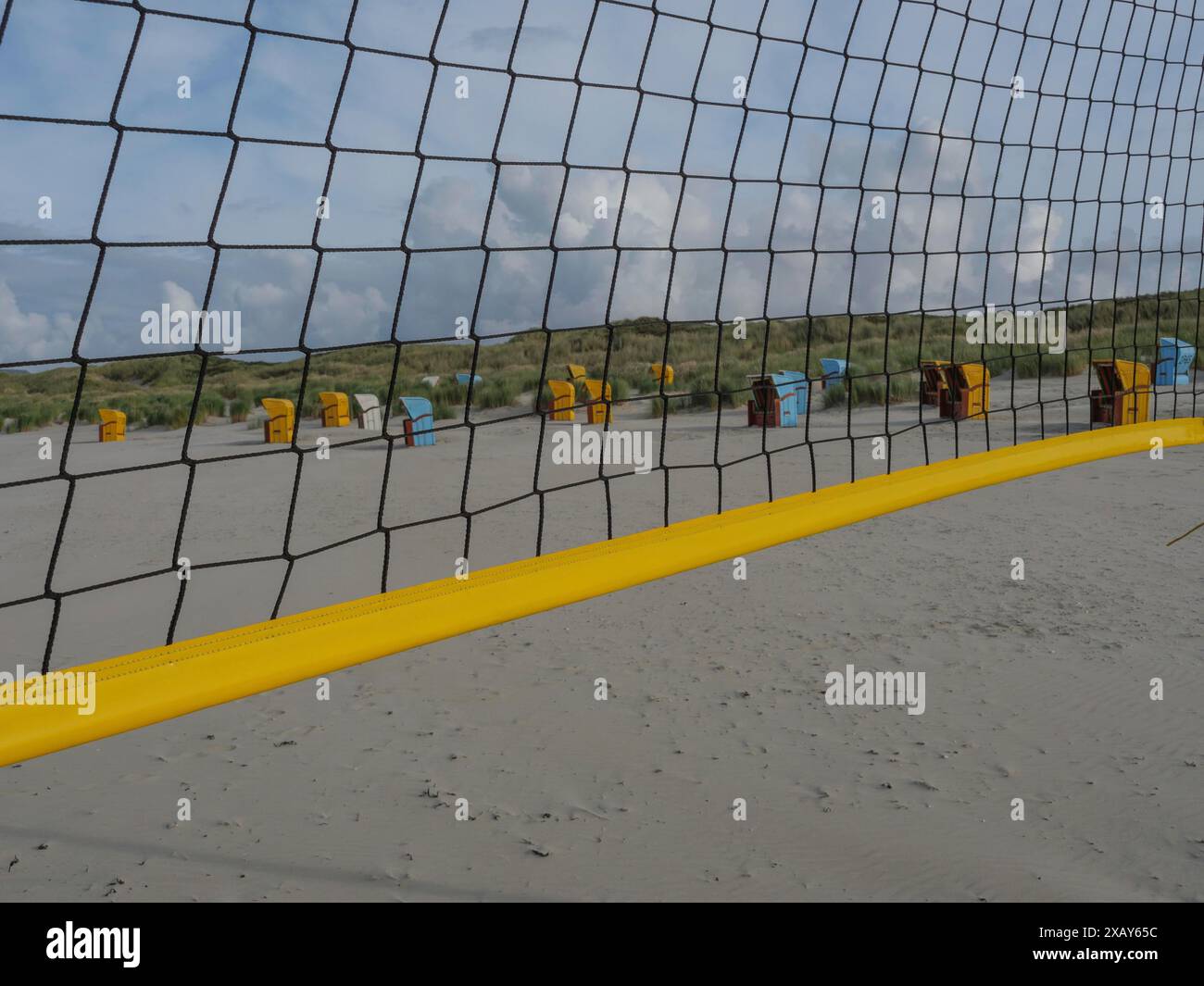 A volleyball net stretches across the beach, with dunes and beach ...