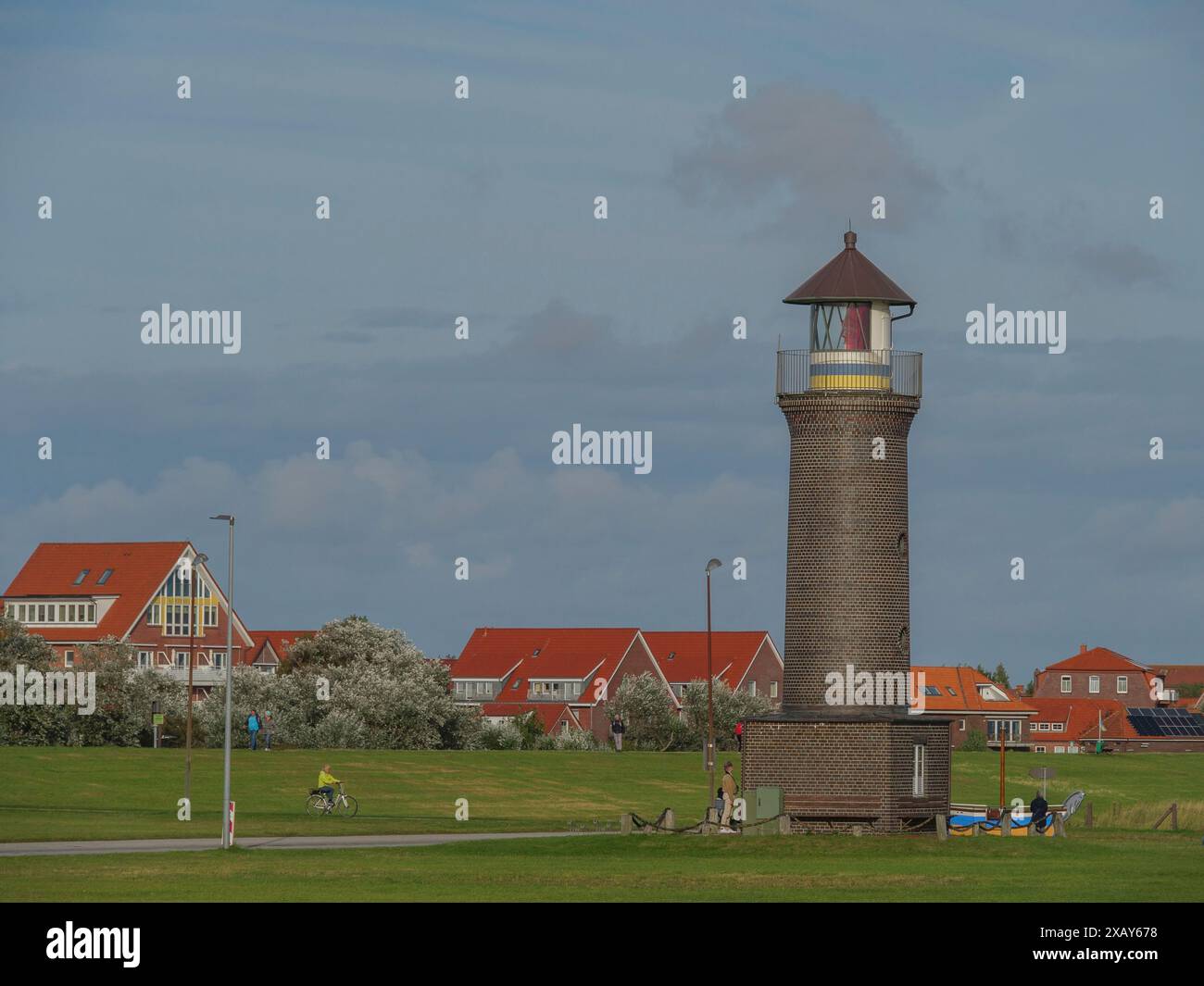 A lighthouse stands in the middle of a grassy area, with houses in the ...
