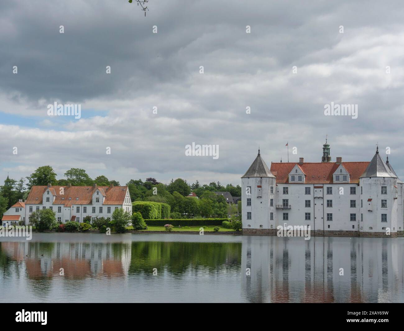 A historic castle with white facades and red roofs is reflected in a ...