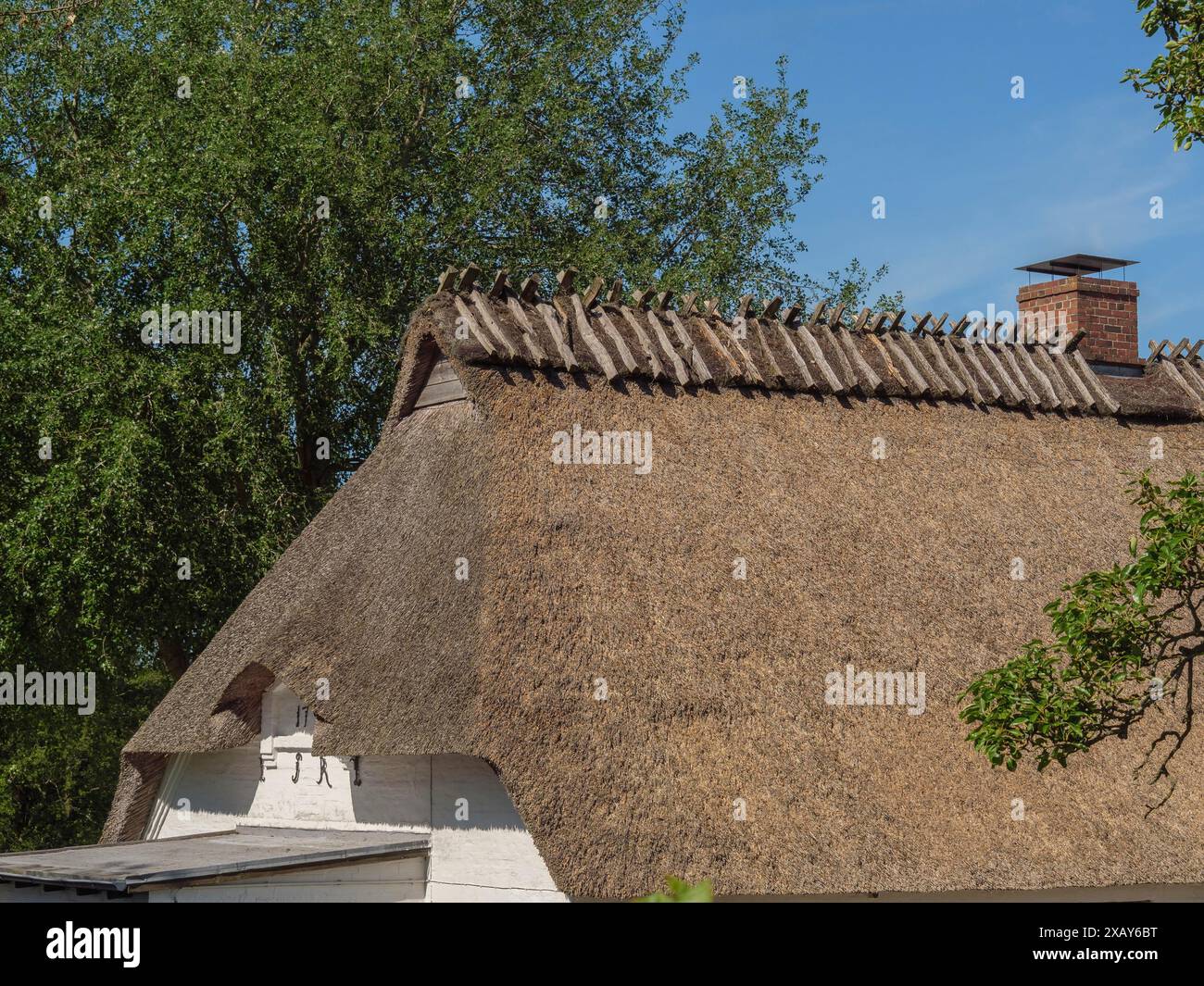 Traditional house with thatched roof and brick fireplace in front of a ...