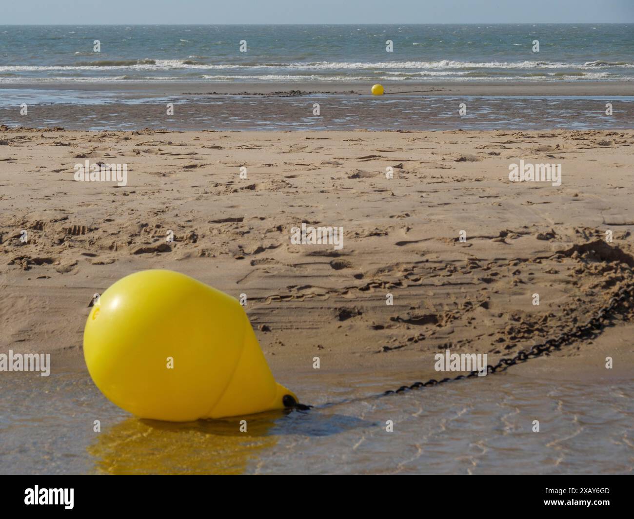 A large yellow buoy lies in the sand on the beach, the sea in the ...