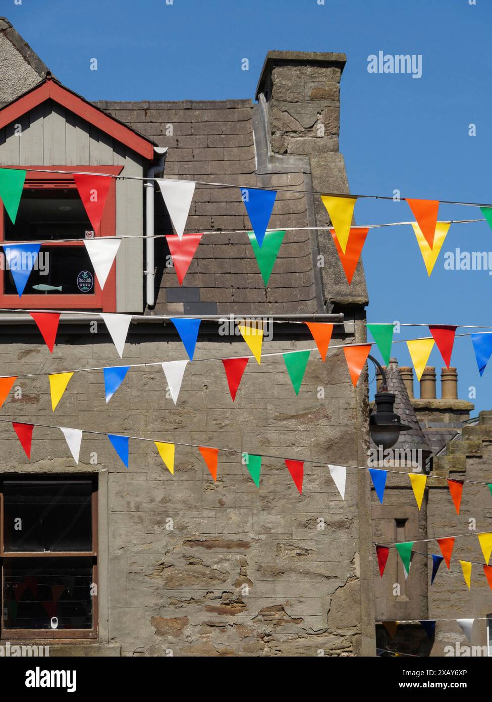 A house decorated with colourful flags under a clear blue sky, with ...