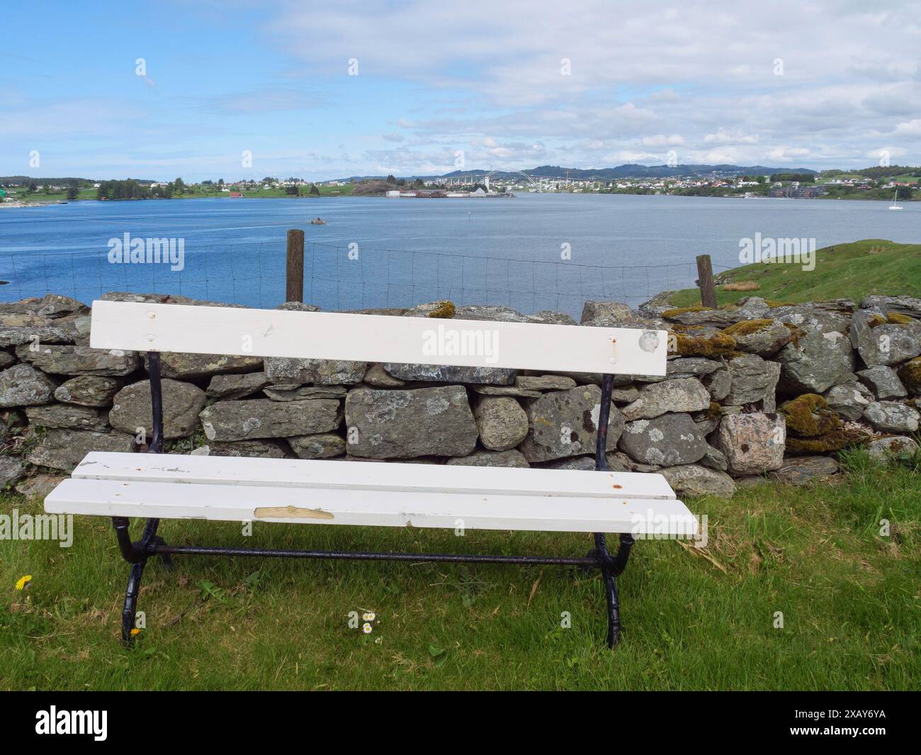 Park bench in front of a stone wall with a view of a lake and a town on ...
