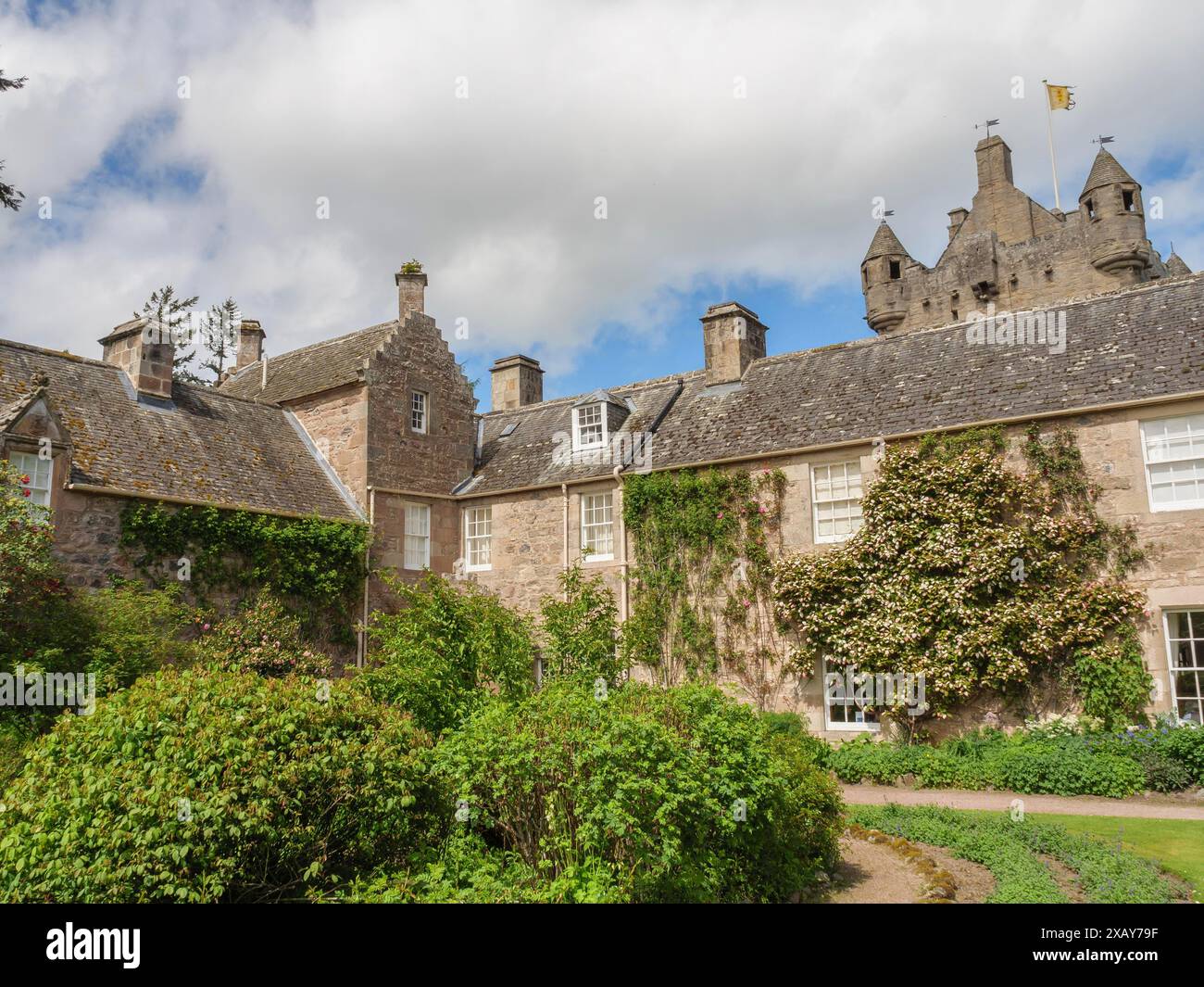 Historic stone house with climbing plants and garden, part of a larger ...