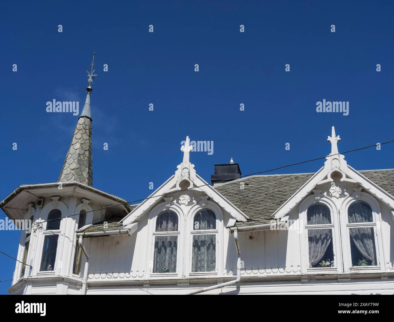 A white building with Gothic towers and decorative windows under a blue ...