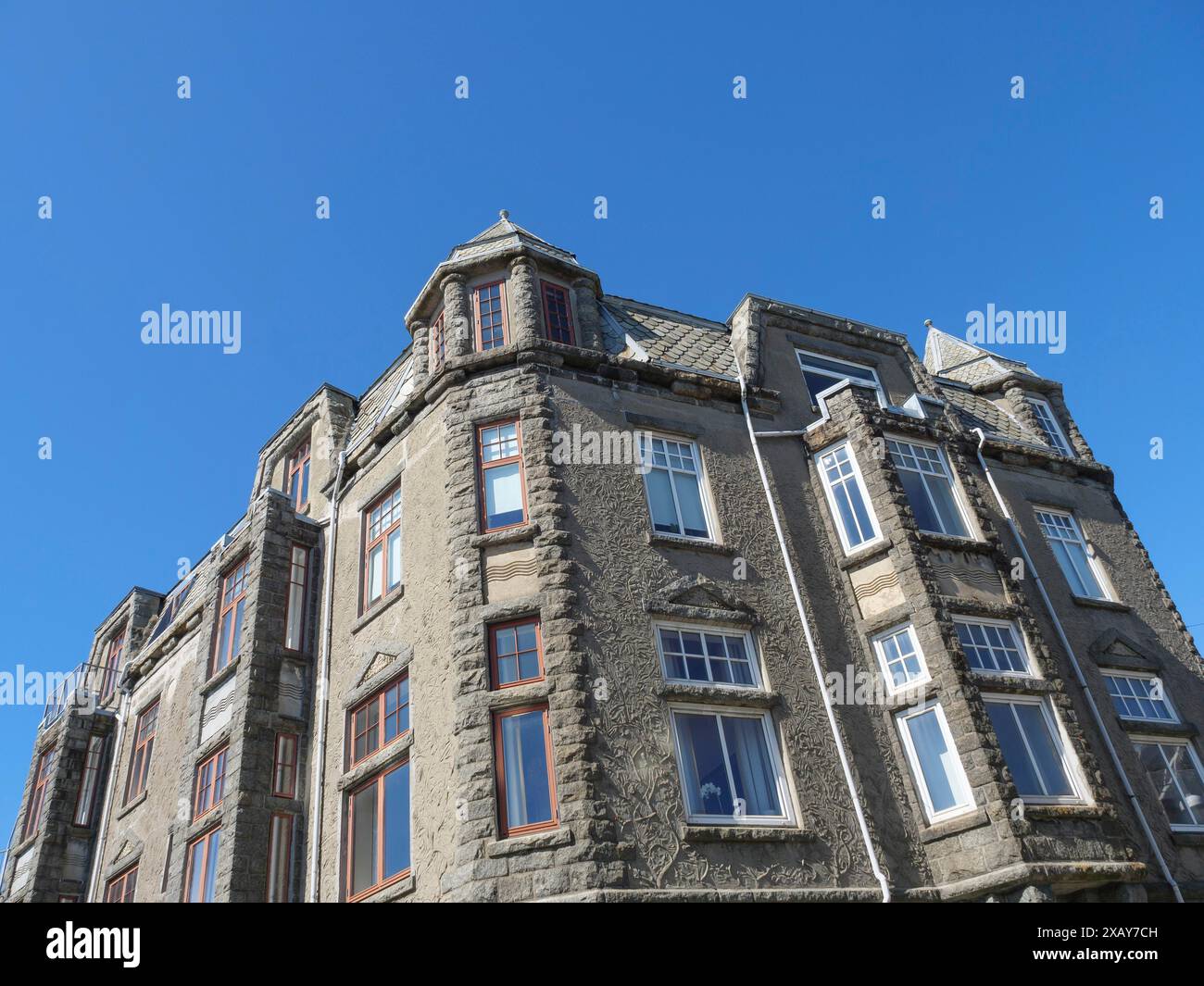 A historic stone building with Gothic windows under a clear blue sky ...