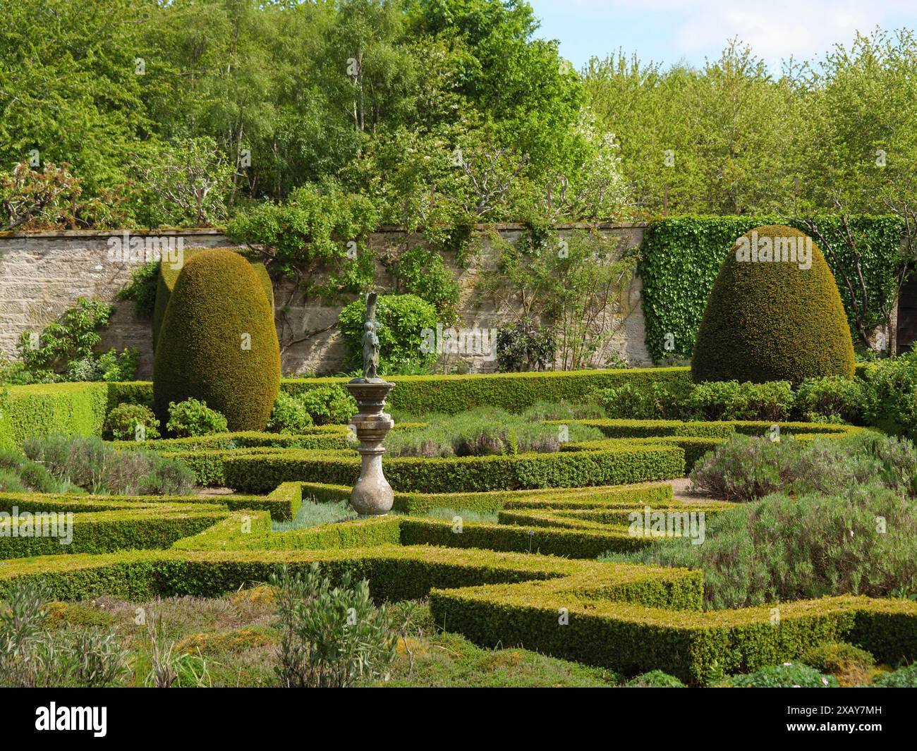 A manicured garden with symmetrical hedges and a centrally placed ...