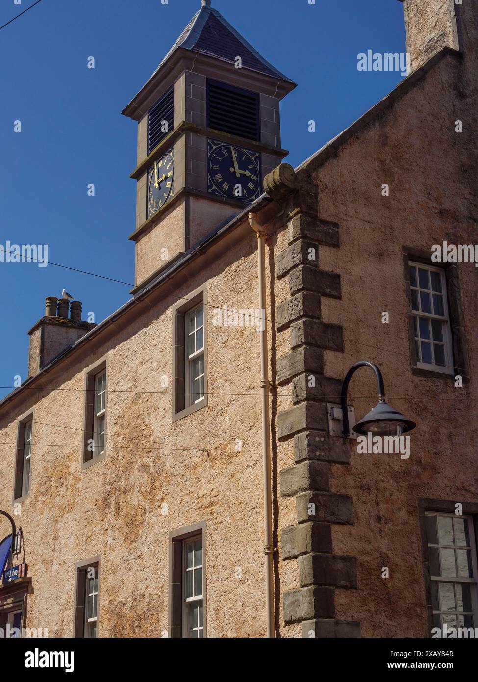 A historic building with clock tower and sunny facade under a blue sky ...