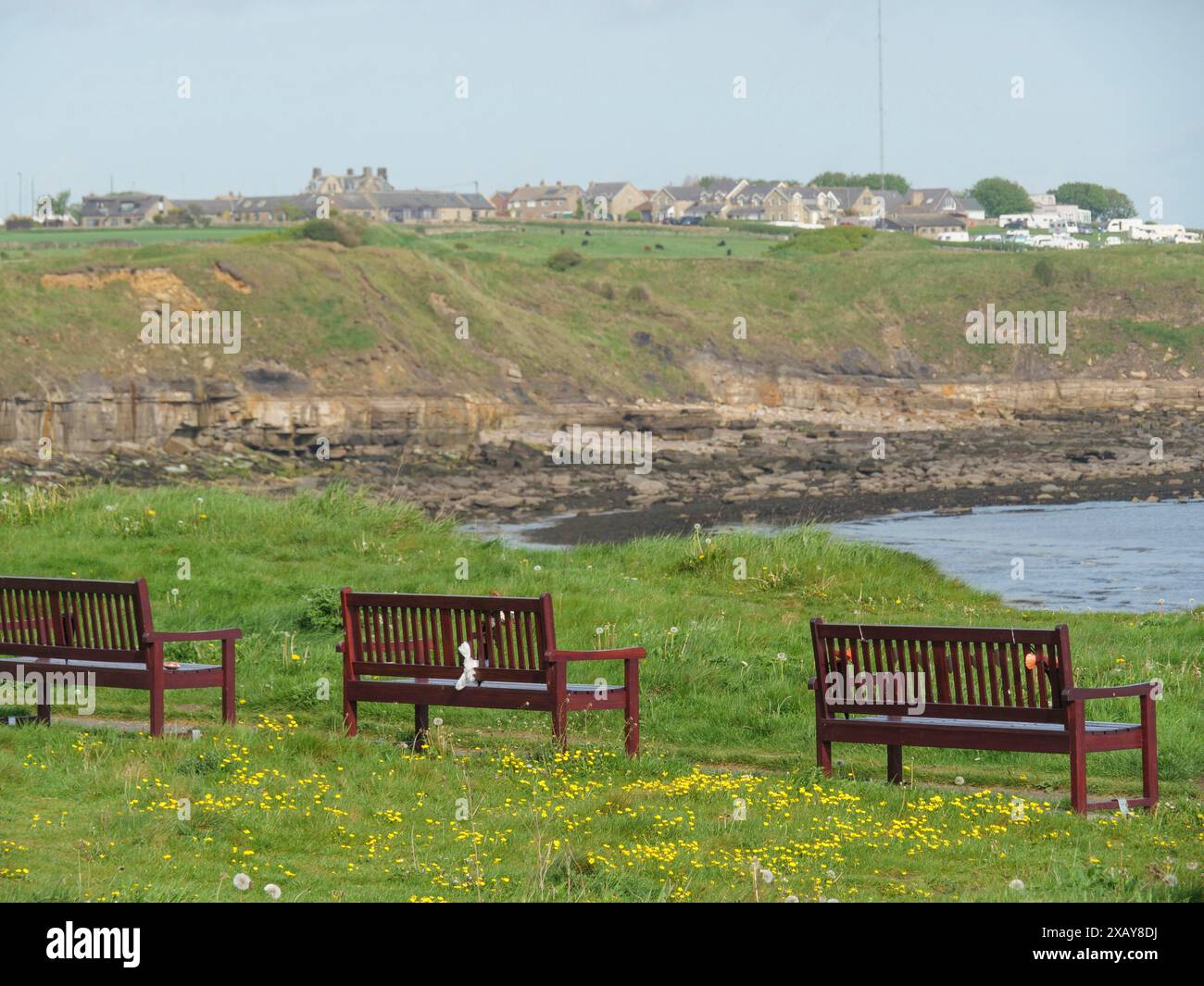 Park benches with views of the coast, green hills and distant houses ...