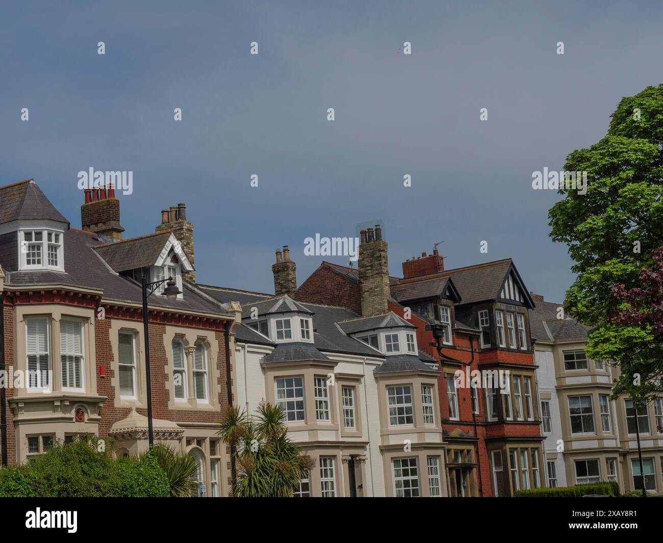 Row of traditional houses with brick walls and windows under a blue sky ...